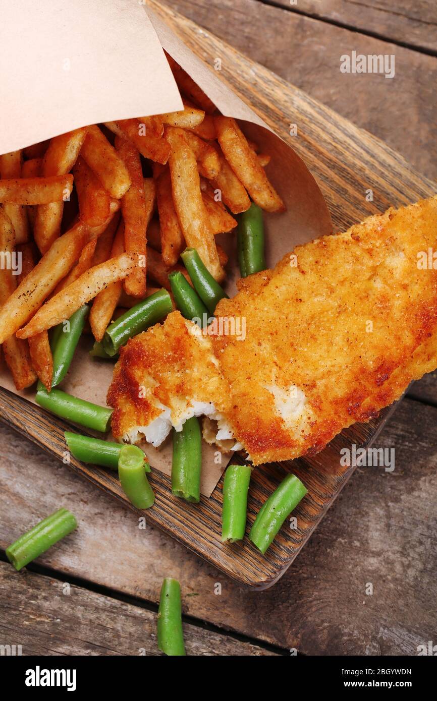 Breaded fried fish fillet and potatoes in paper bag with asparagus on ...