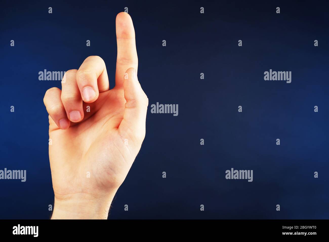 Male hand pointing up on dark blue background Stock Photo - Alamy