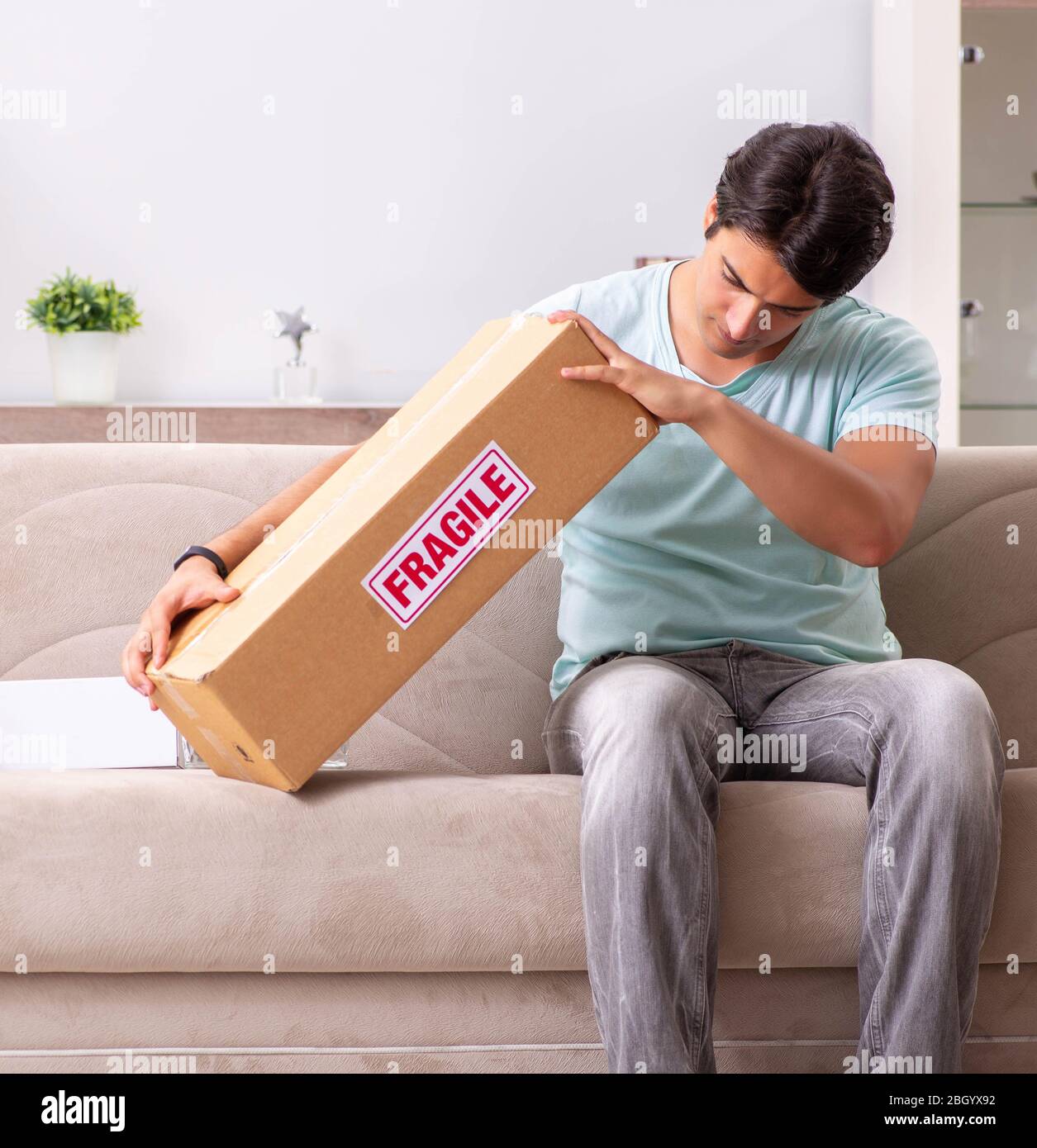The man opening fragile parcel ordered from internet Stock Photo - Alamy