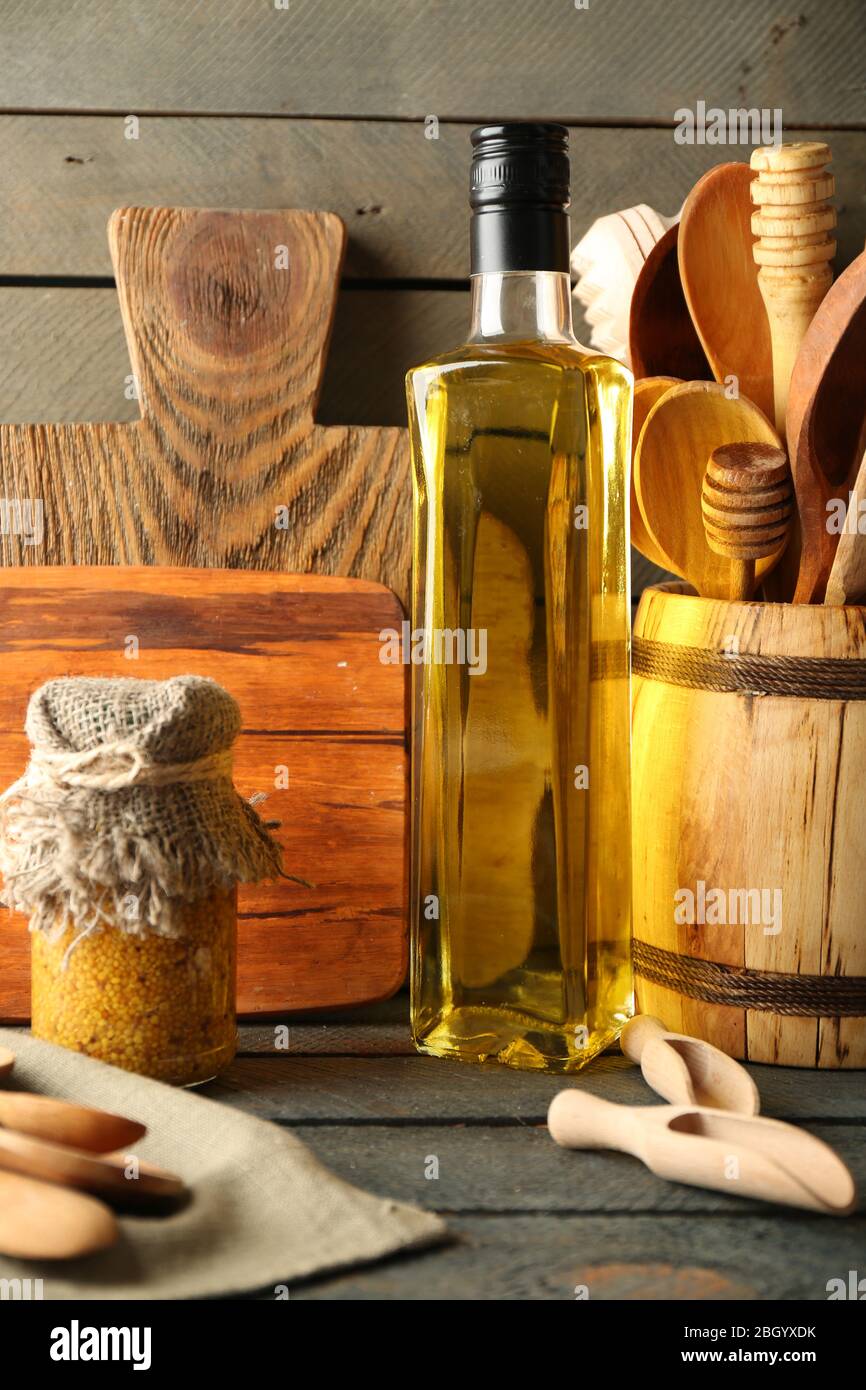 Wooden kitchen utensils with glass bottle of olive oil on wooden planks ...