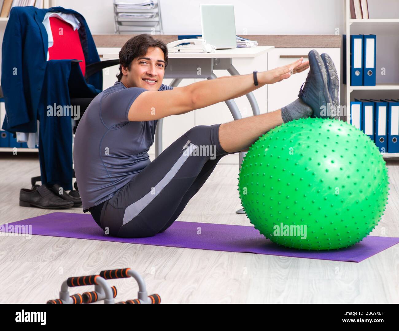 The young male employee exercising in the office Stock Photo - Alamy