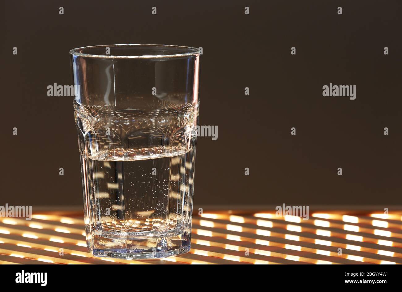 Glass of clean mineral water on lattice surface and dark color ...
