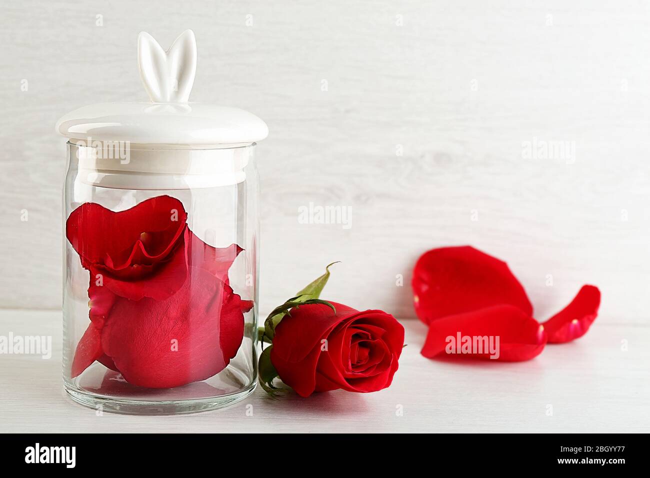 Rose flower in glass jar on light background Stock Photo - Alamy
