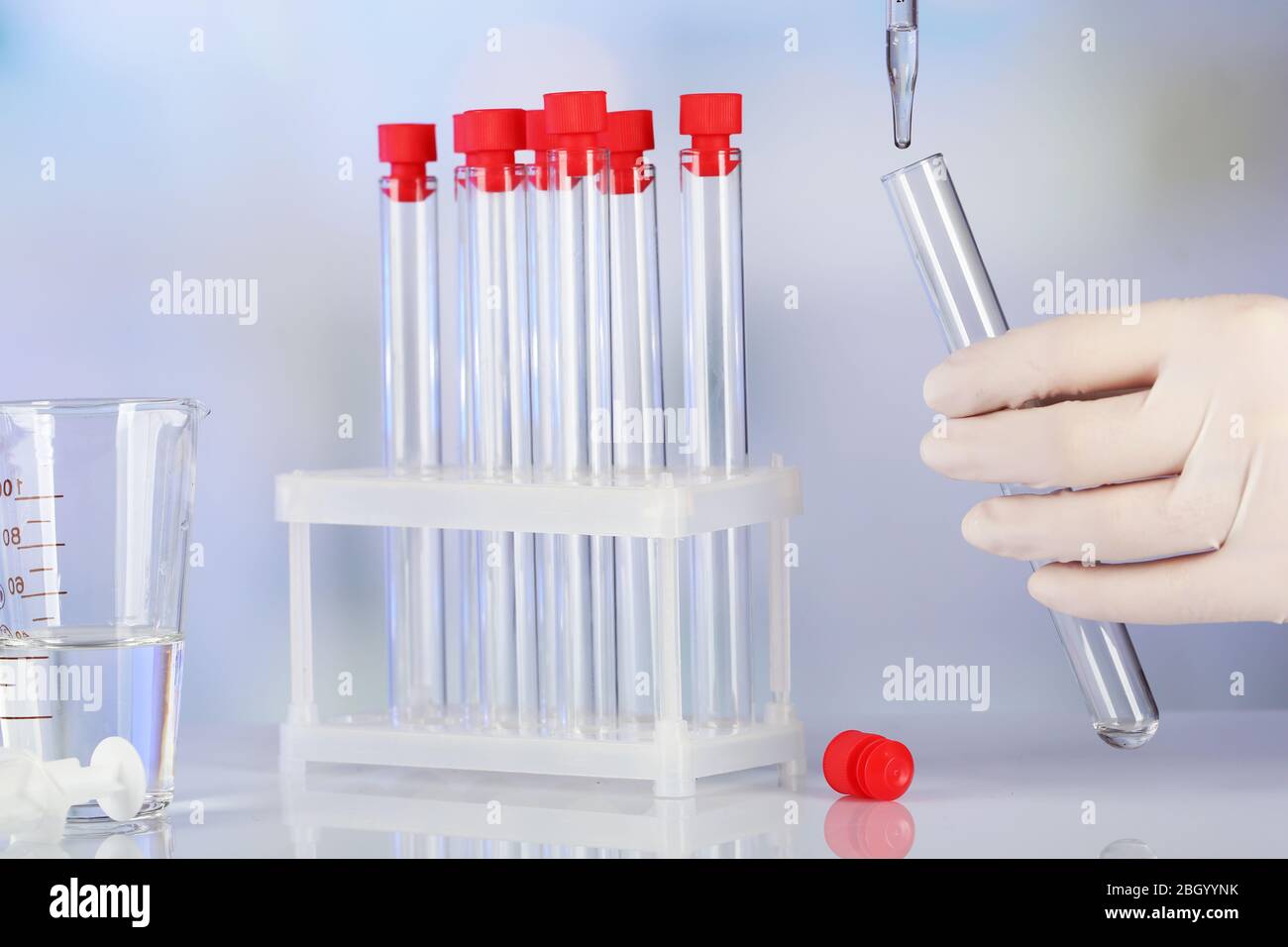 Hand of assistant with liquid in test tubes during experiment in ...