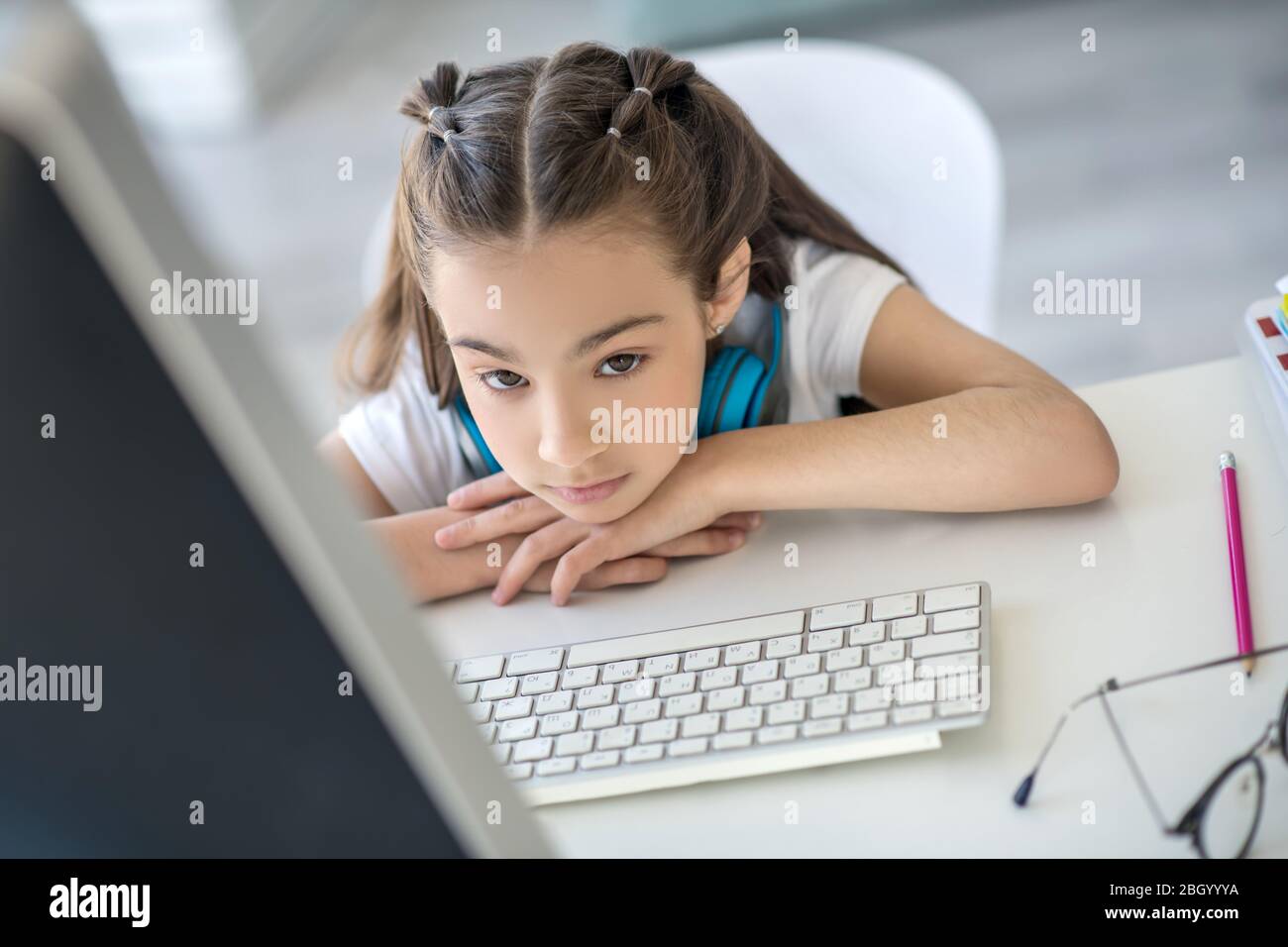 Long-haired girl sitting at the table and looking bored Stock Photo - Alamy
