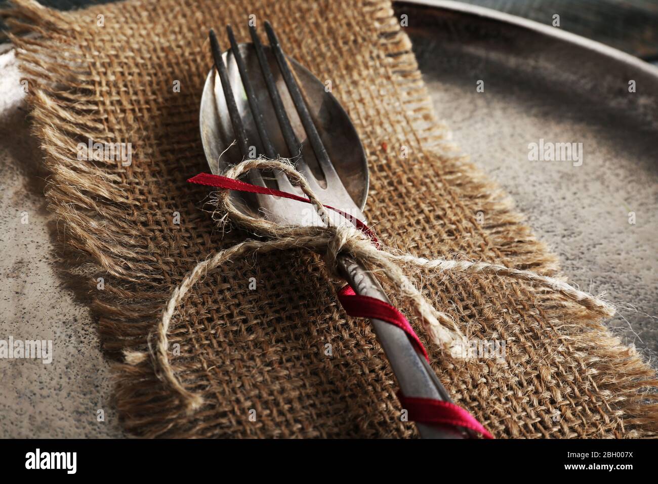Silverware tied with rope on burlap cloth and metal tray background ...