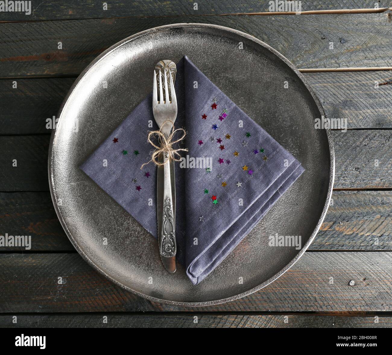 Silverware tied with rope on napkin and metal tray and wooden planks ...