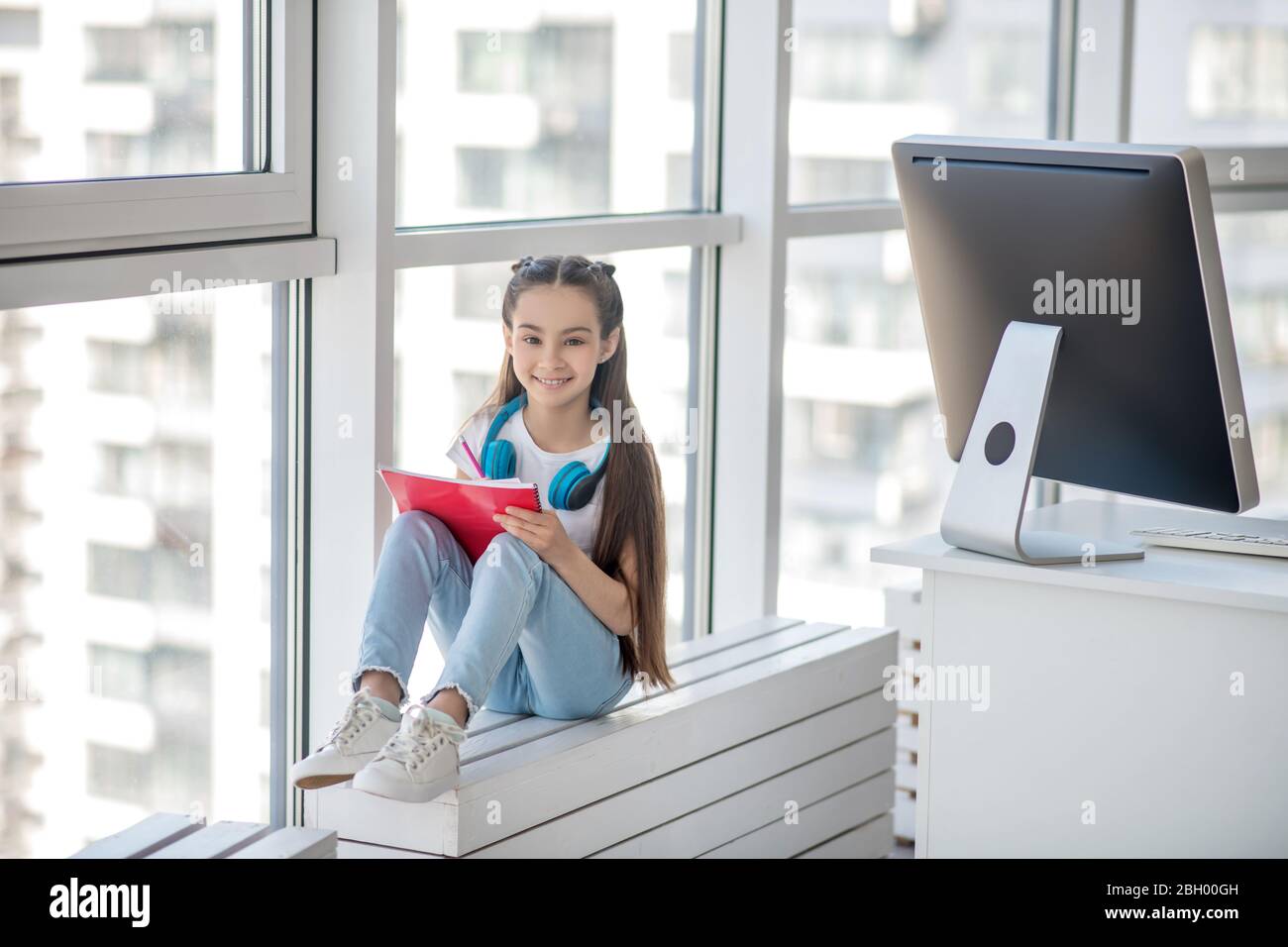 Long-haired girl in white tshirt sitting the window Stock Photo - Alamy