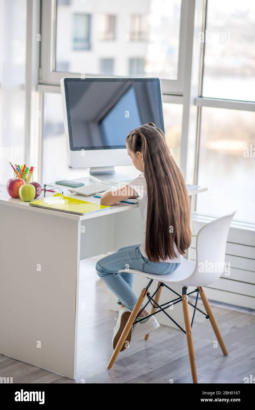 Long-haired teen sitting at the table and studying Stock Photo - Alamy