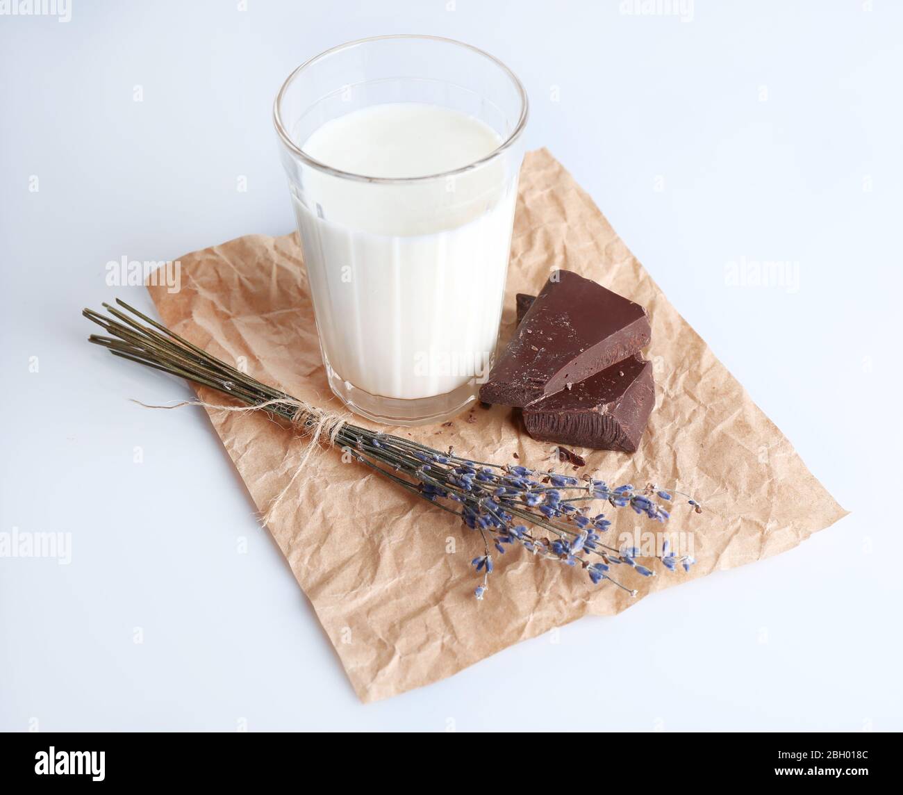 Glass of milk with chocolate chunks on sheet of crumpled paper isolated ...