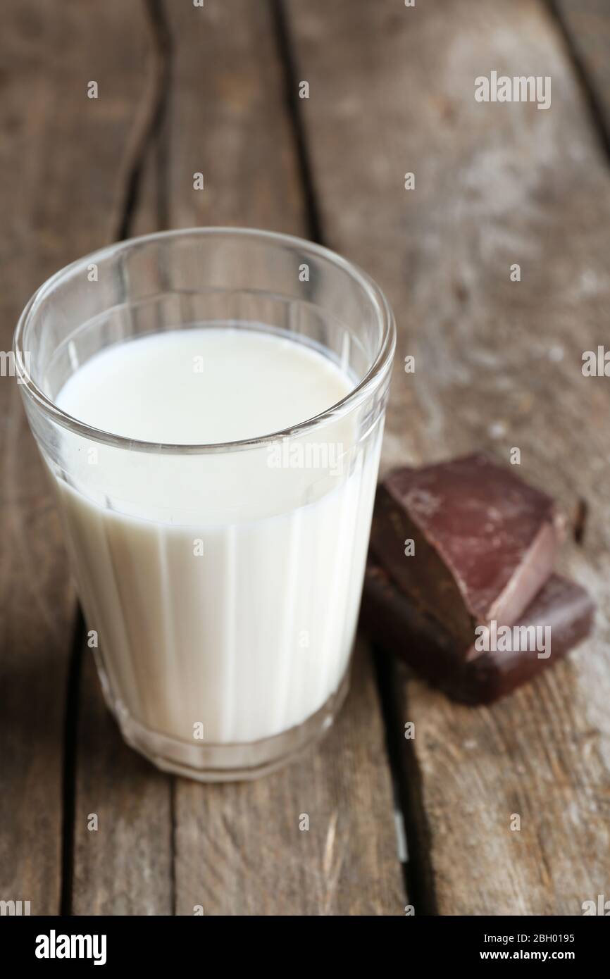 Glass of milk with chocolate chunks on rustic wooden planks background ...