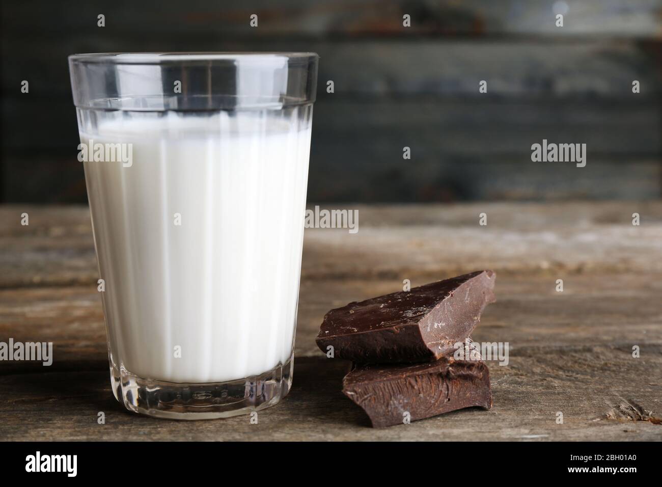 Glass of milk with chocolate chunks on rustic wooden planks background ...
