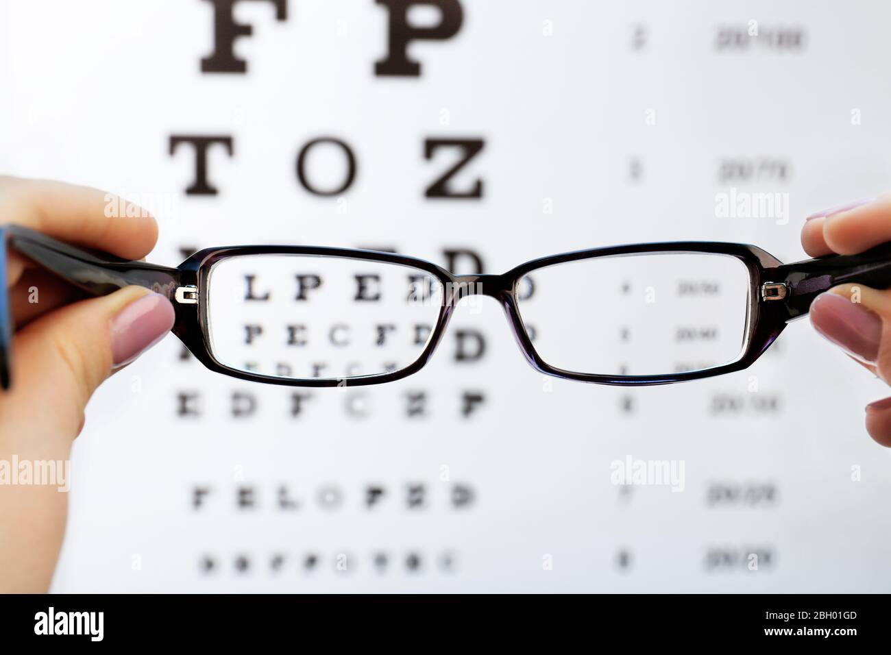 Eye glasses in female hands on eyesight test chart background Stock ...