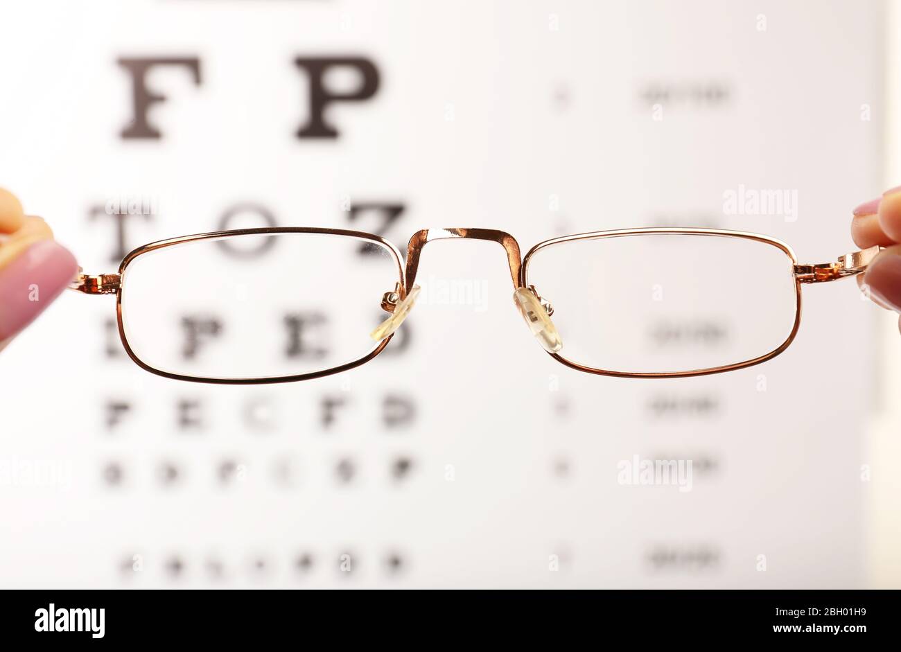 Eye glasses in female hands on eyesight test chart background Stock ...