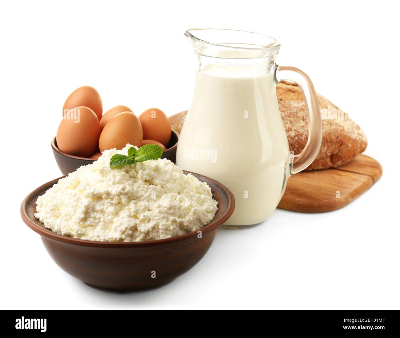 Dairy products in pottery, glass jug of milk, eggs and loaf of bread ...