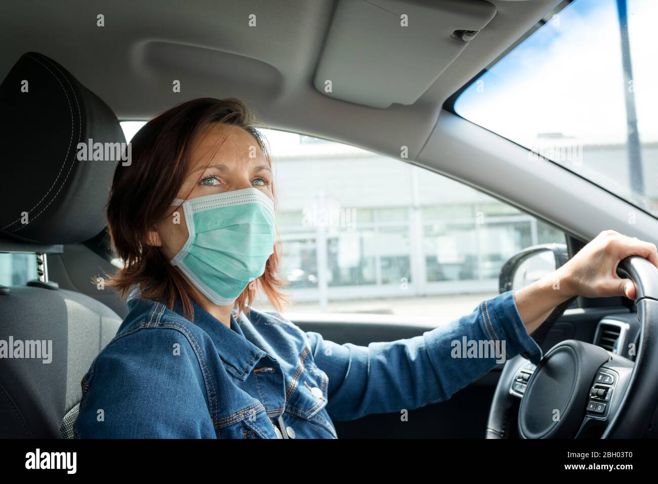 Woman driving her car with a mask on her face Stock Photo - Alamy