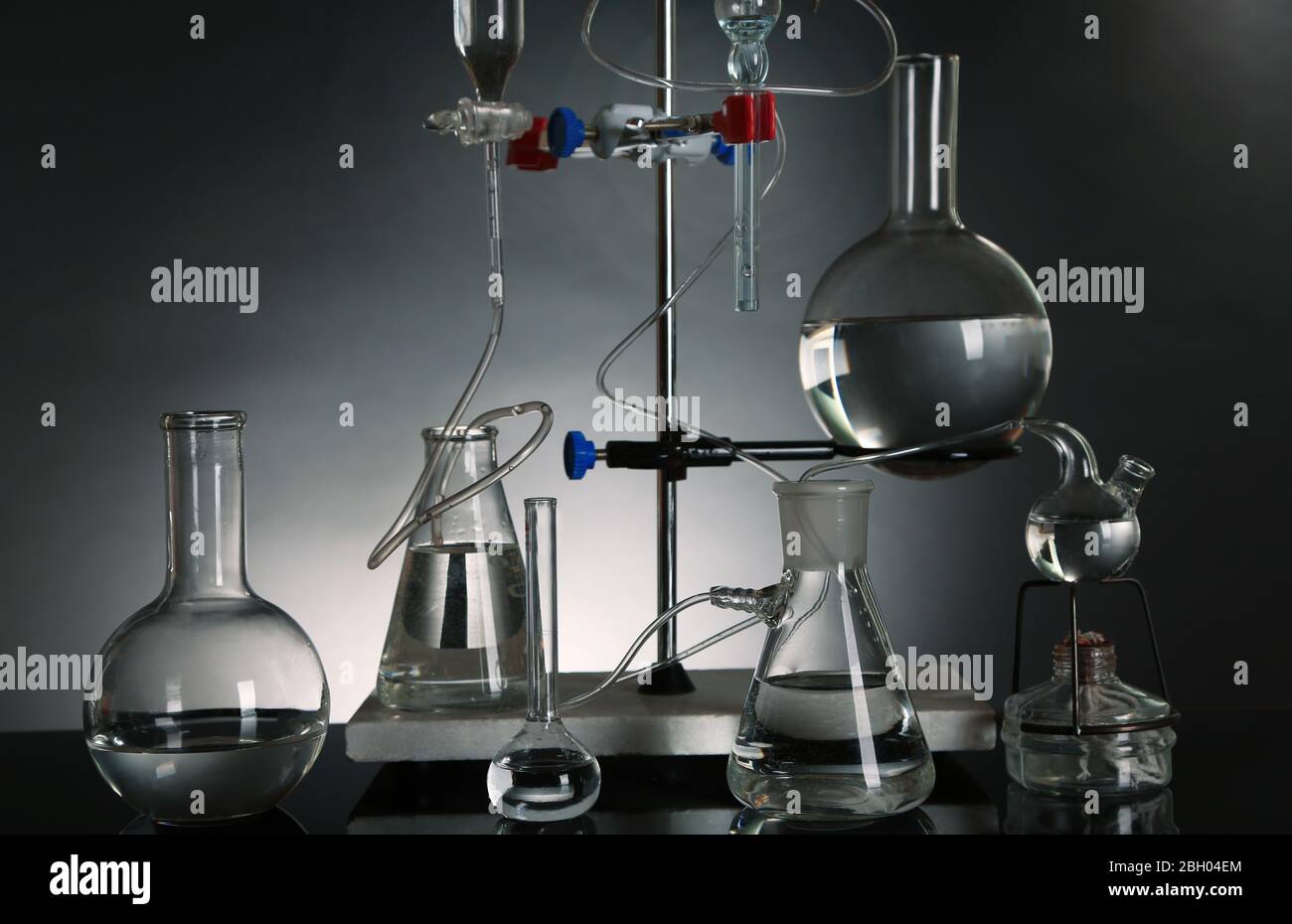 Fixed laboratory glassware on support on dark colorful background Stock ...