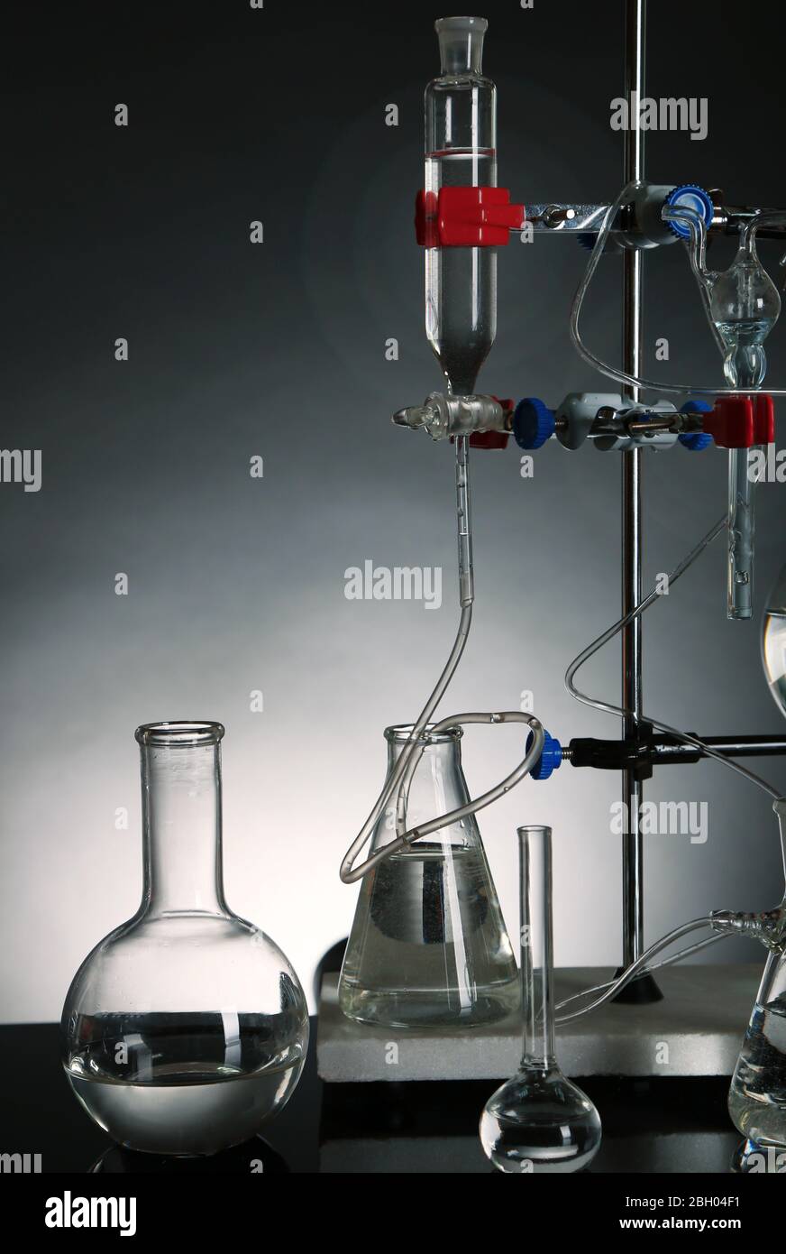 Fixed laboratory glassware on support on dark colorful background Stock ...