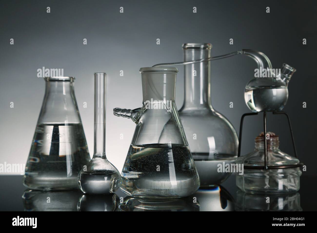 Fixed laboratory glassware on dark background Stock Photo - Alamy