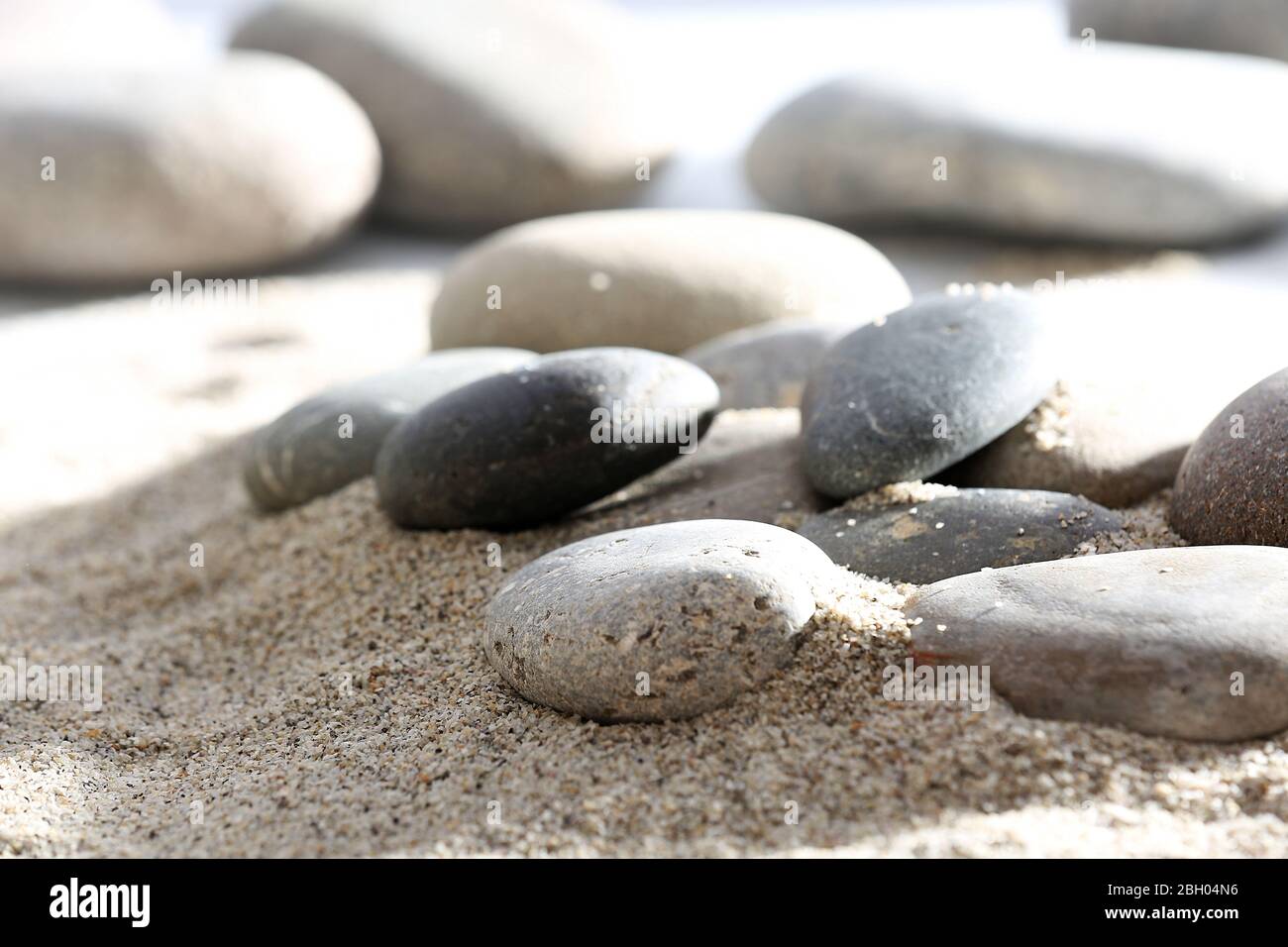 Gray sea pebbles on sand background Stock Photo - Alamy