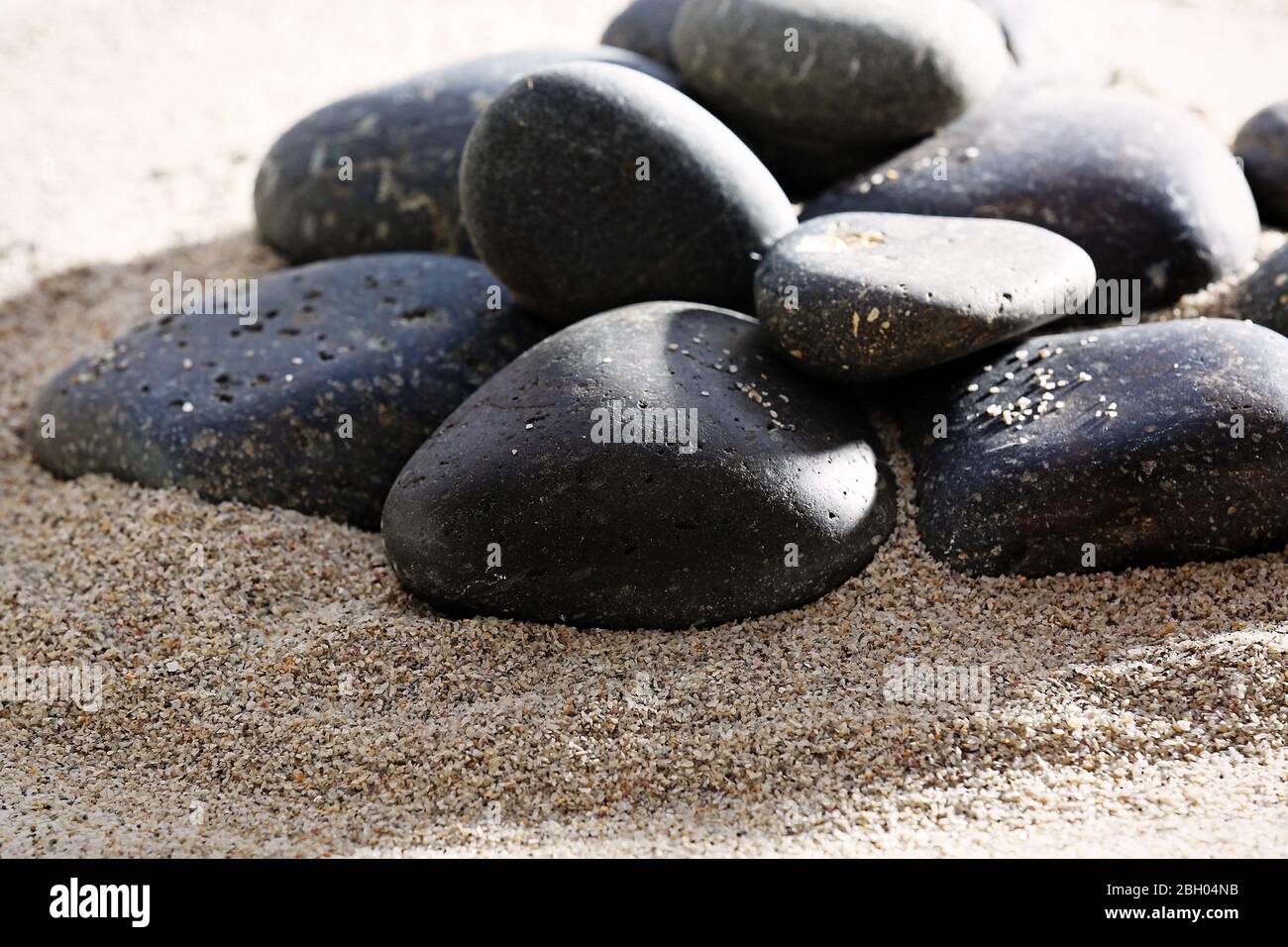 Pile of sea pebbles on shiny sand background Stock Photo - Alamy