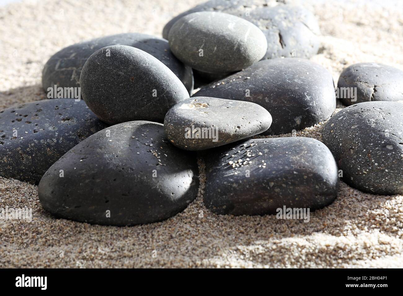 Pile of sea pebbles on shiny sand background Stock Photo - Alamy