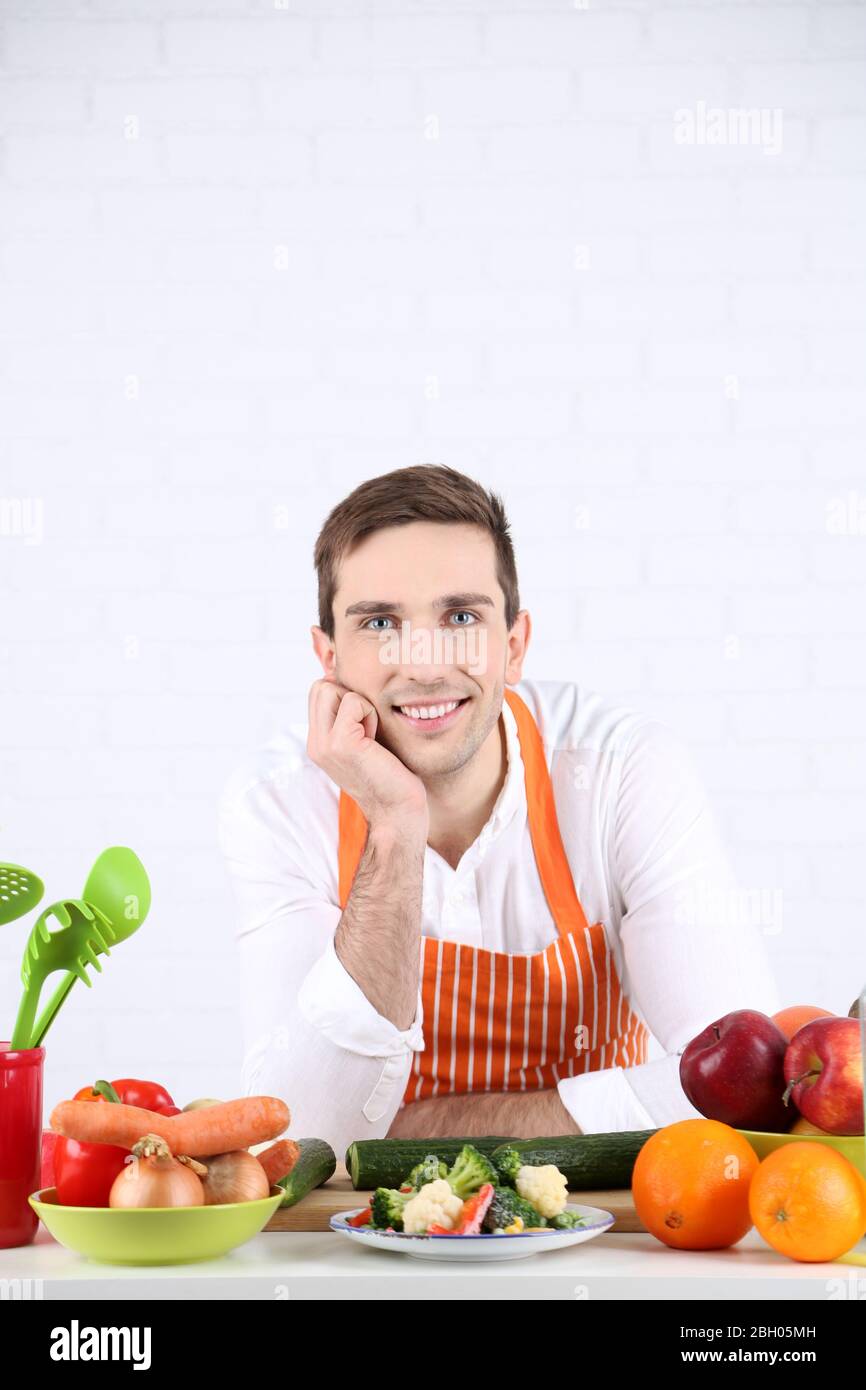 Man at table with different products and utensil in kitchen on white ...