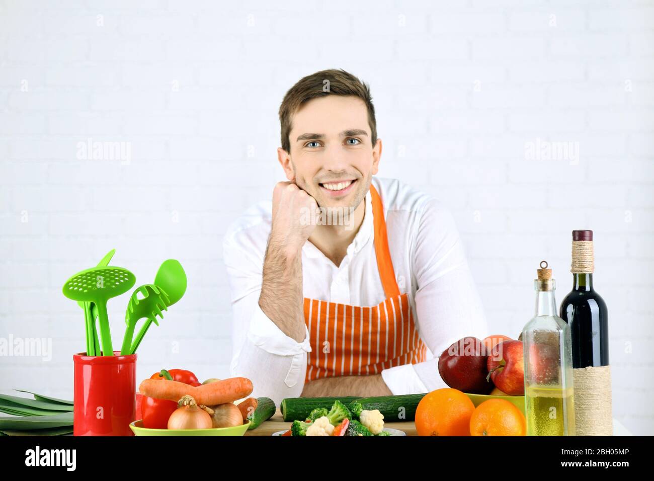 Man at table with different products and utensil in kitchen on white ...
