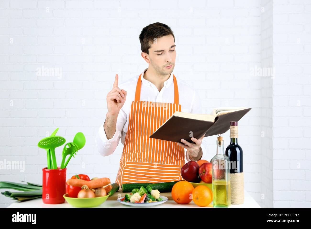Man with recipe book in hands at table with different products and ...