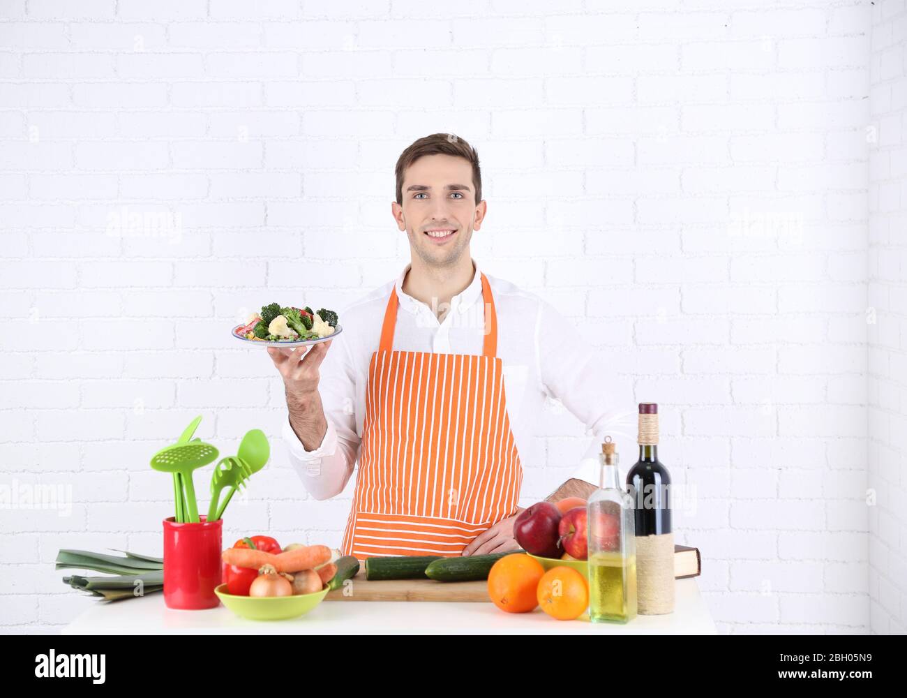 Man at table with different products and utensil in kitchen on white ...