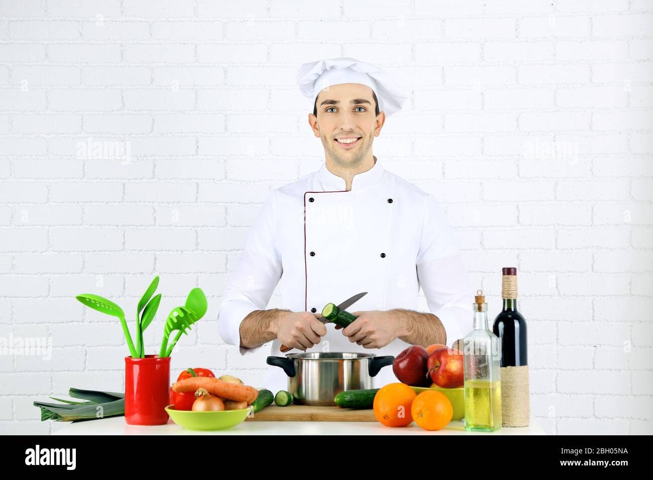 Chef at table with different products and utensil in kitchen on white ...
