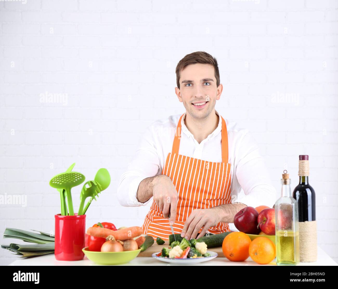 Man at table with different products and utensil in kitchen on white ...