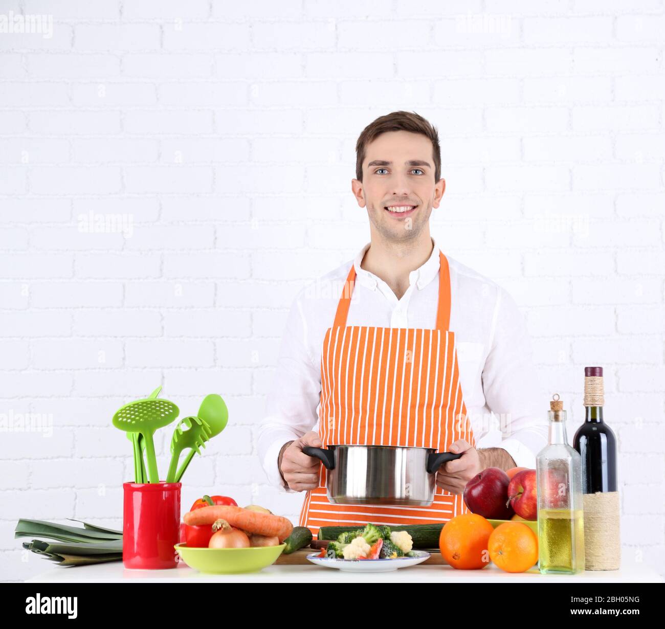 Man at table with different products and utensil in kitchen on white ...