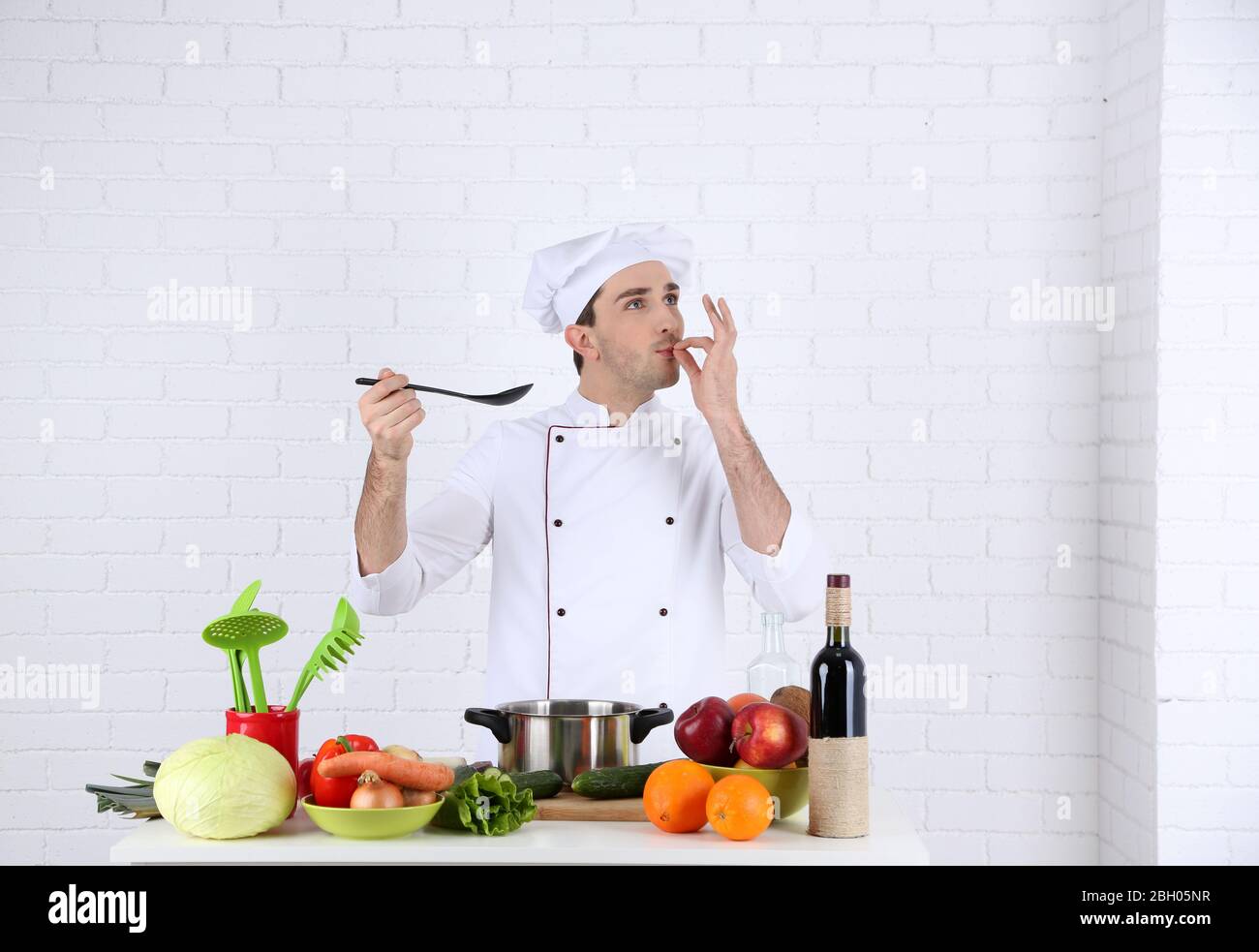 Chef at table with different products and utensil in kitchen on white ...