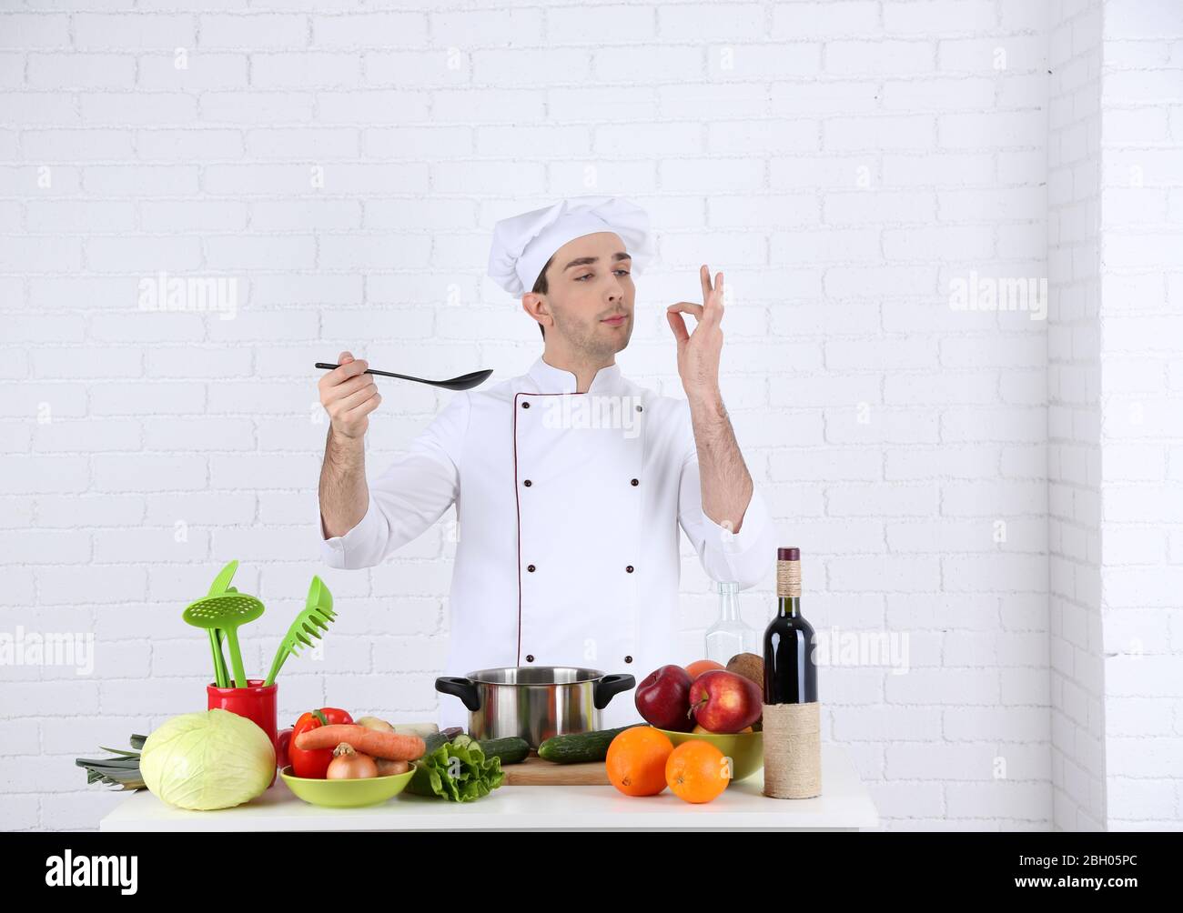 Chef at table with different products and utensil in kitchen on white ...