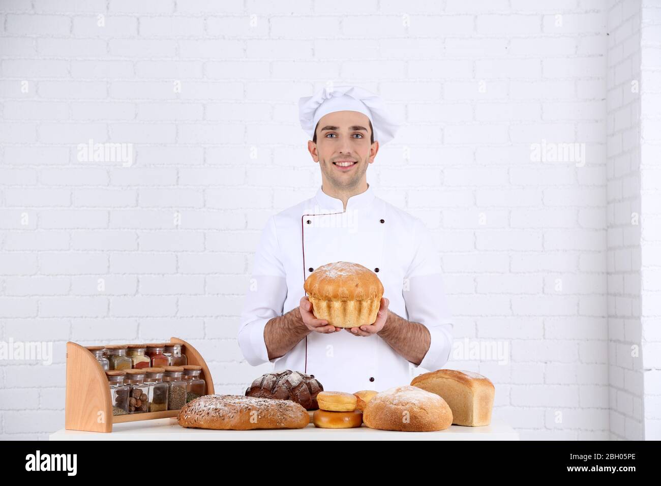 Baker in kitchen at table with freshly loaves of bread on white brick ...