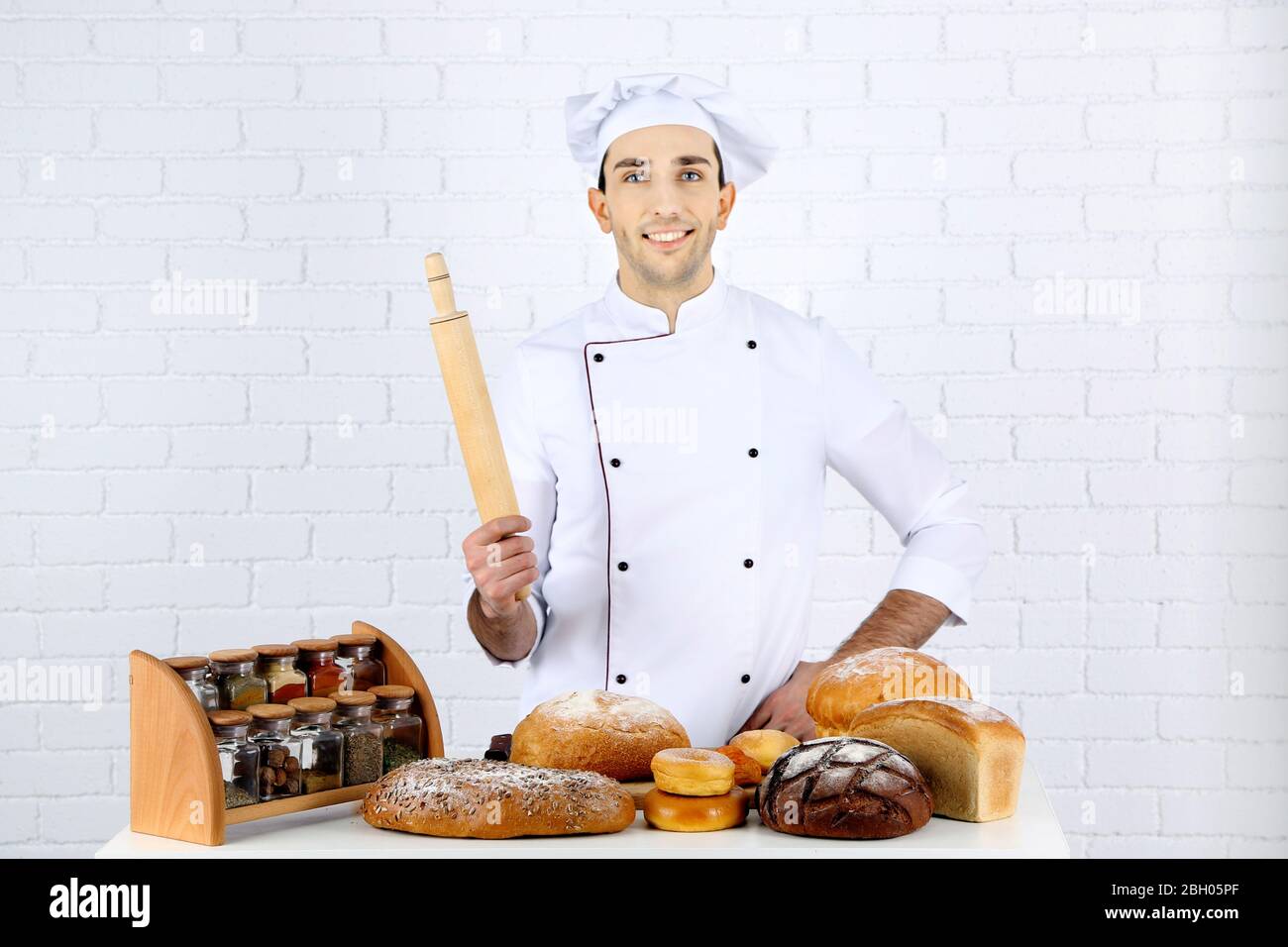 Baker in kitchen at table with freshly loaves of bread on white brick ...