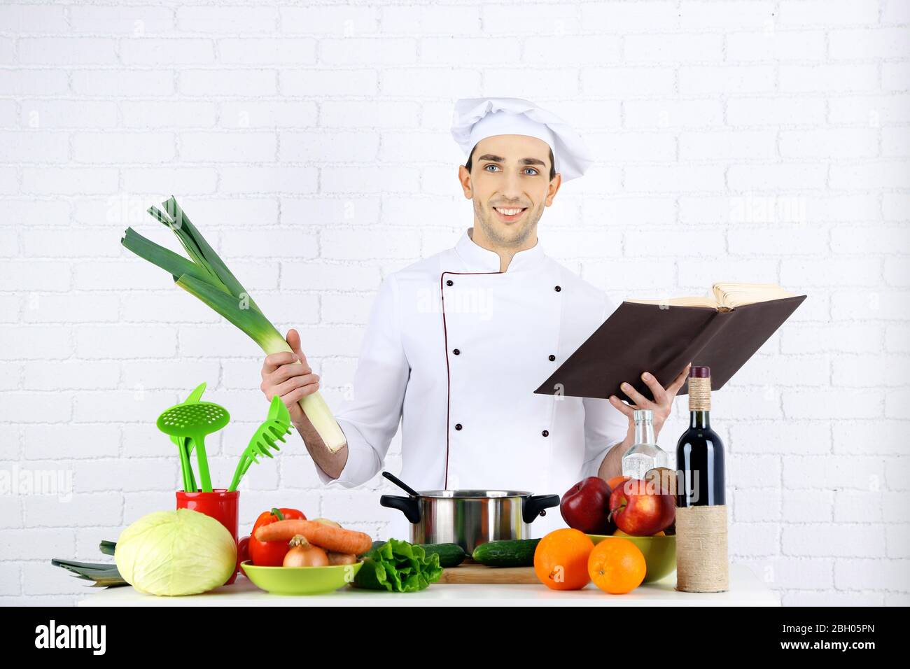 Chef at table with different products and utensil in kitchen on white ...