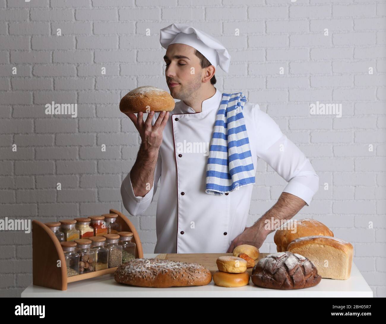 Baker in kitchen at table with freshly loaves of bread on white brick ...