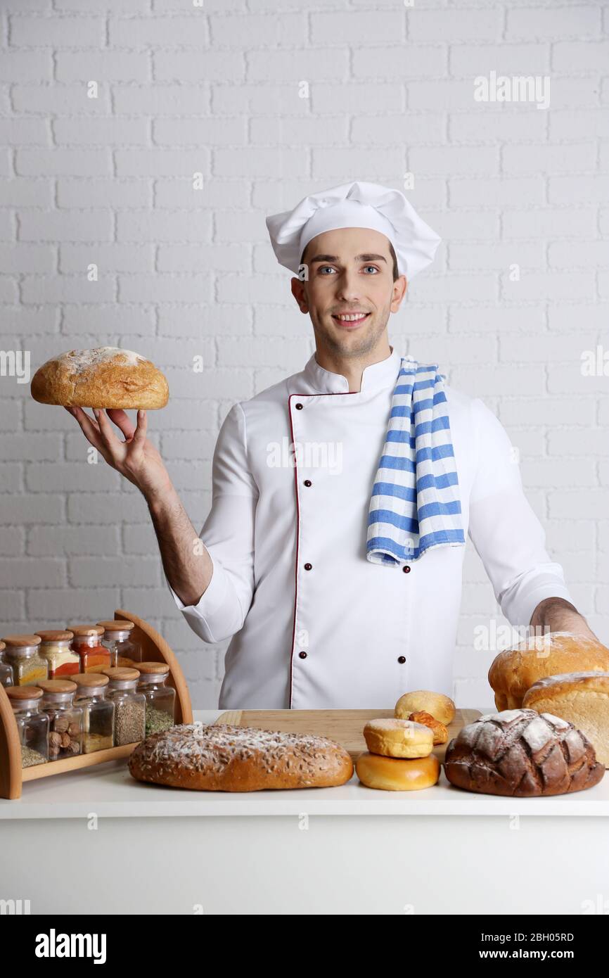 Baker in kitchen at table with freshly loaves of bread on white brick ...