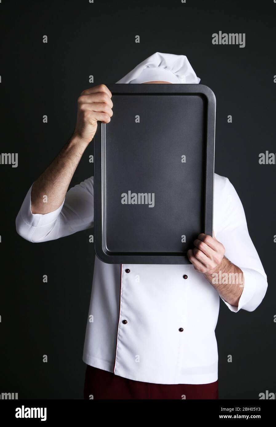 Portrait of chef with oven pan behind his face on dark background Stock ...