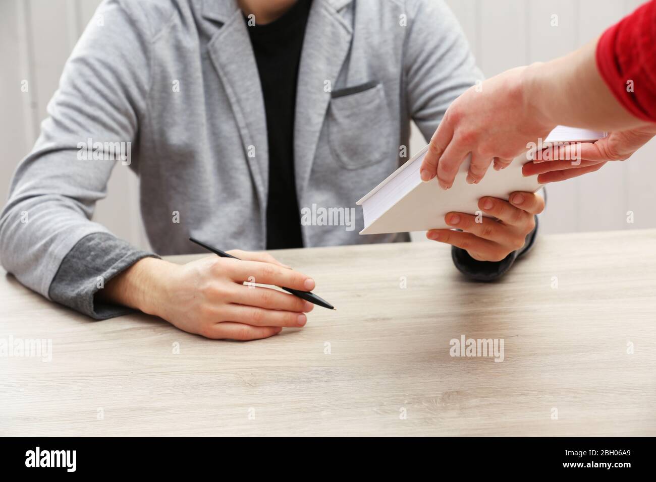Author signing autograph in own book at wooden table on white planks ...