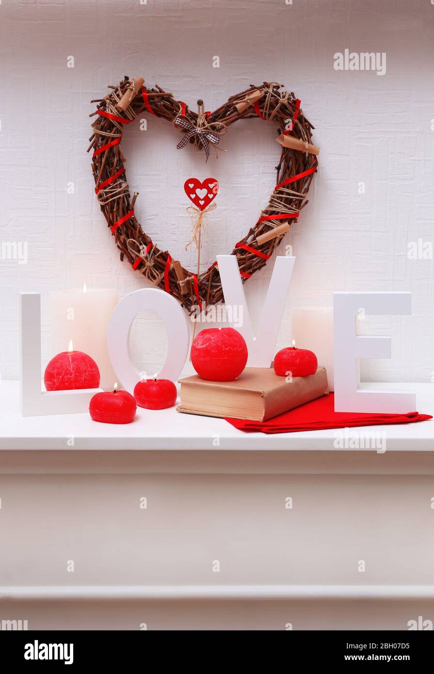 Romantic still life with wicker heart and candle lights on mantelpiece ...