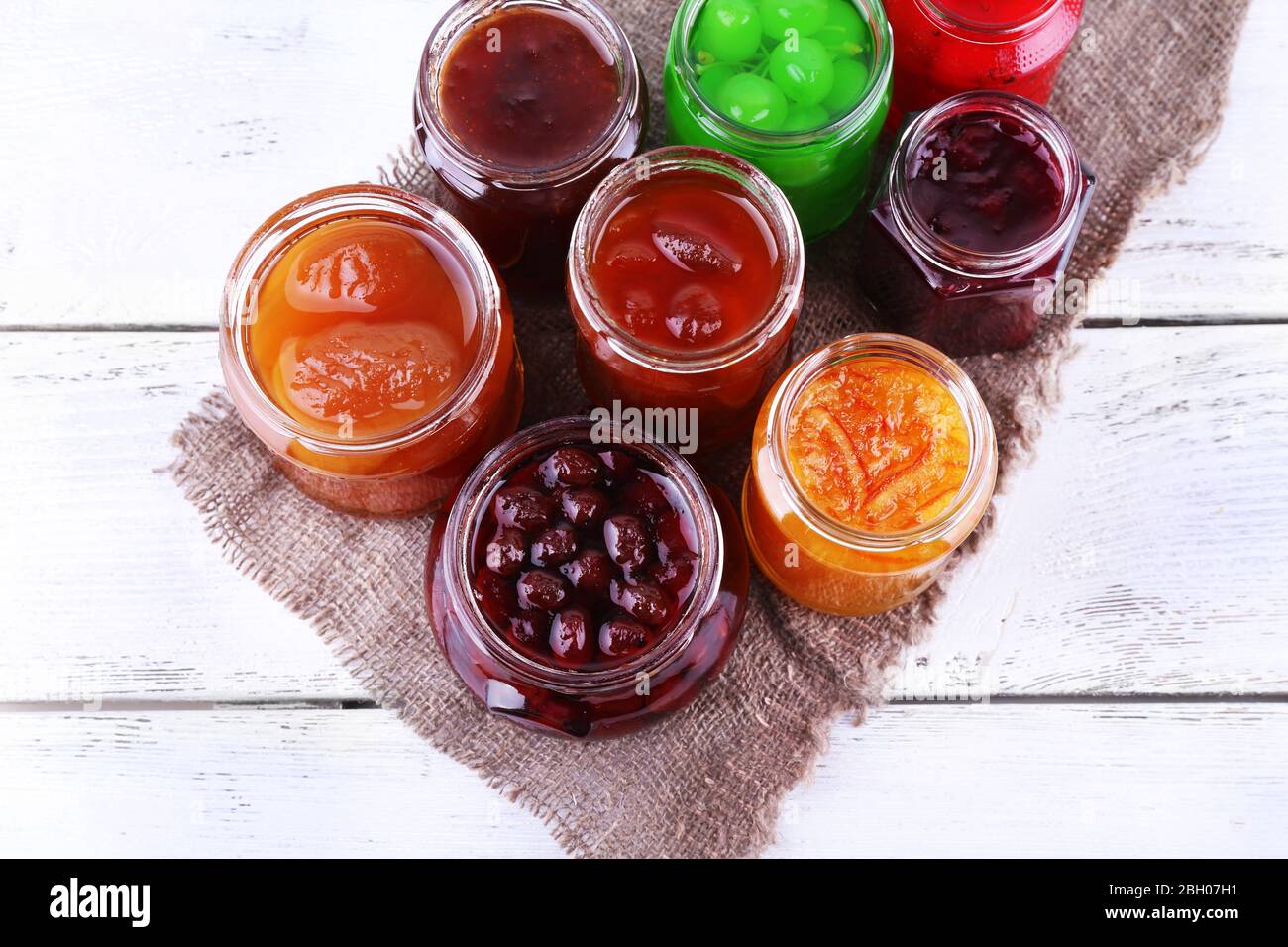 Homemade jars of fruits jam on color wooden planks background Stock ...