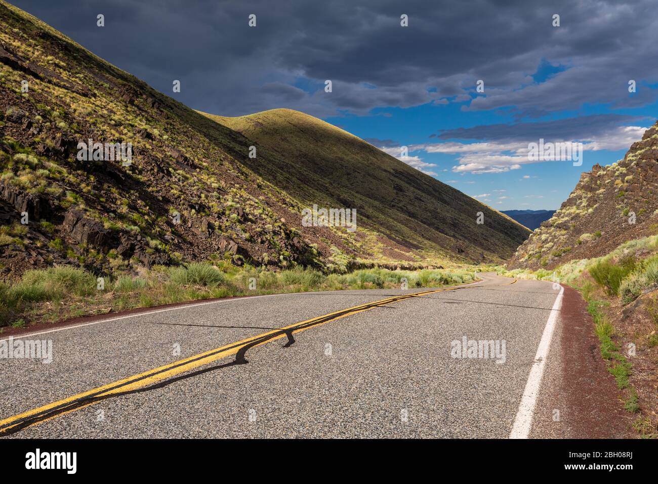 Low angle view of a remote country road snaking its way between hills ...
