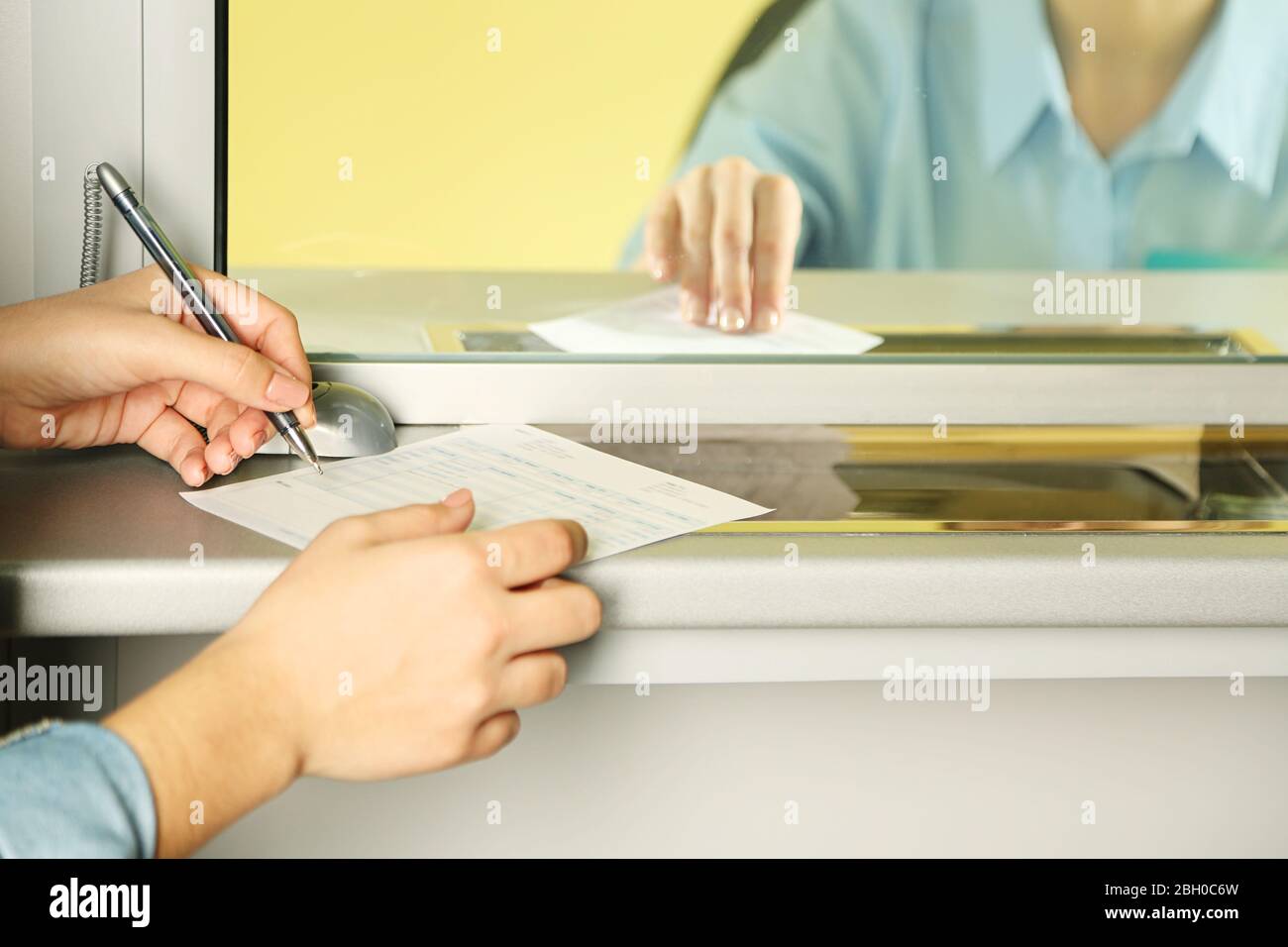 Teller window with working cashier and female hands with claim check ...