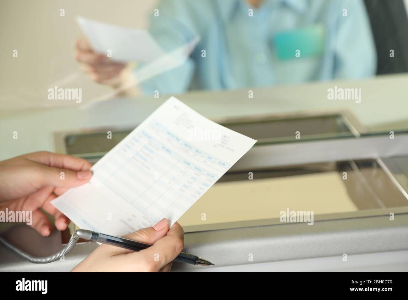 Teller window with working cashier and female hands with claim check ...