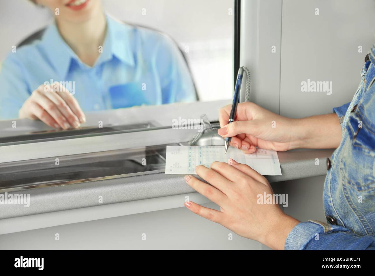 Teller window with working cashier and female hands with claim check ...