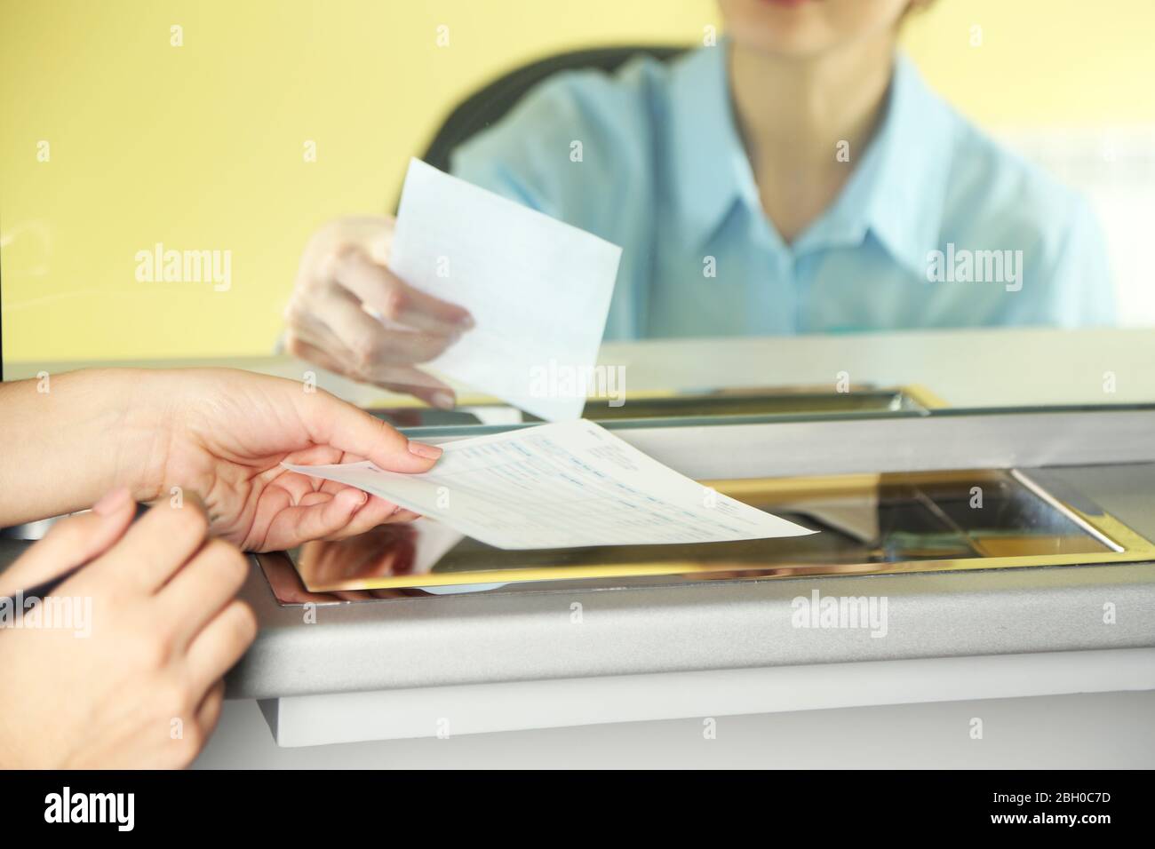 Teller window with working cashier and female hands with claim check ...