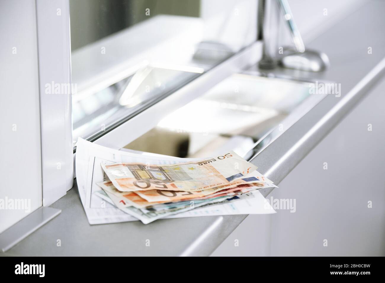 Money on surface near cash department window Stock Photo - Alamy